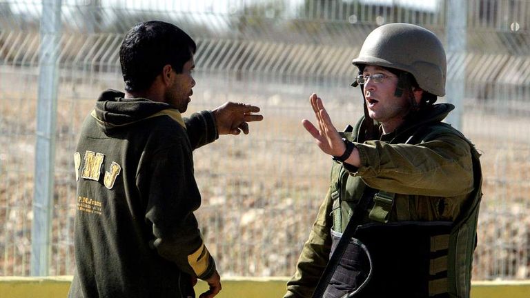 ISRAELI SOLDIER AND PALESTINIAN MAN GESTURE AT CHECKPOINT NEAR WESTBANK ...