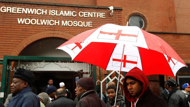 A man with a St George flag umbrella walks among worshippers leaving ...