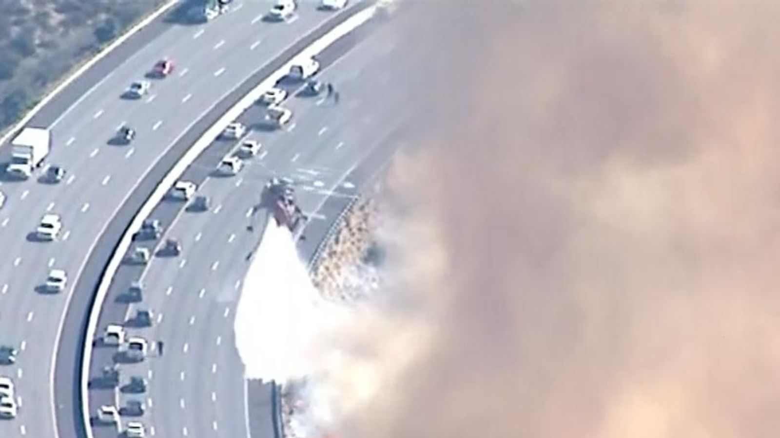 Helicopter dumps water as fire lashes freeway in California's Simi ...