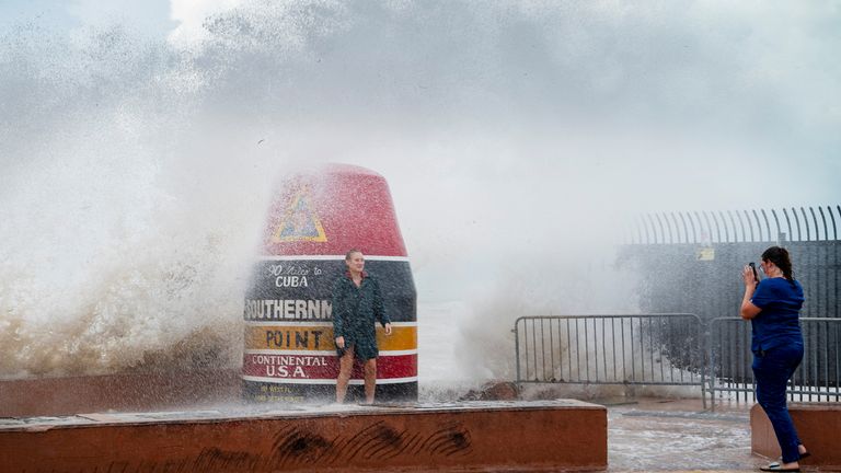 Visitors to the Southernmost Point buoy brave the waves for a few cell ...
