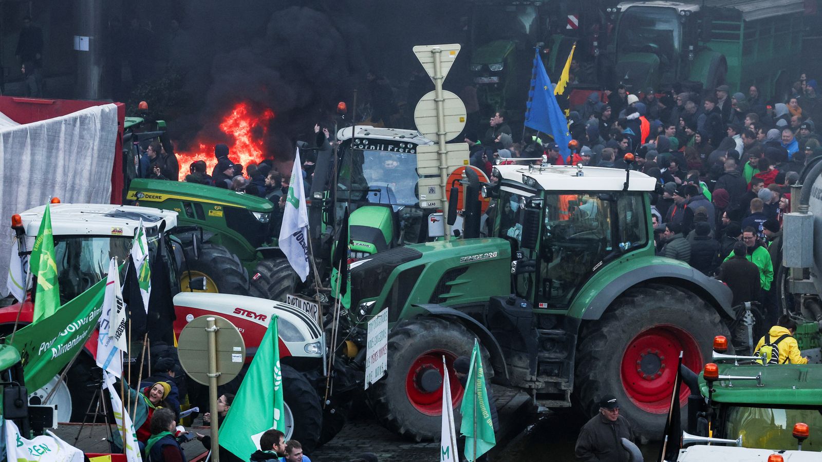 Firecrackers explode and thick smoke fills the air as seething farmers arrive at Brussels' door ...