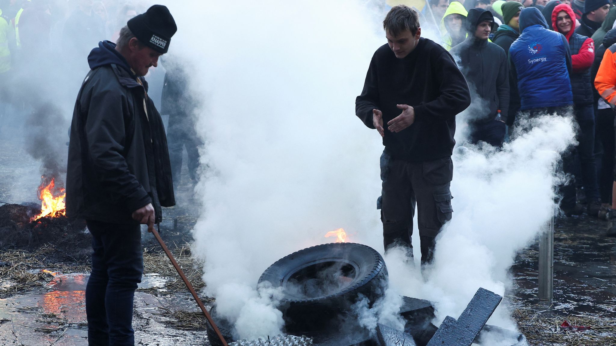 Firecrackers explode and thick smoke fills the air as seething farmers arrive at Brussels' door ...